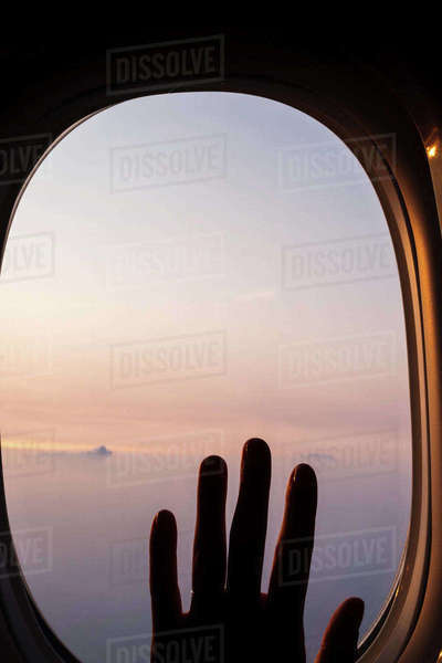 Hand touching airplane window. - Stock Photo - Dissolve