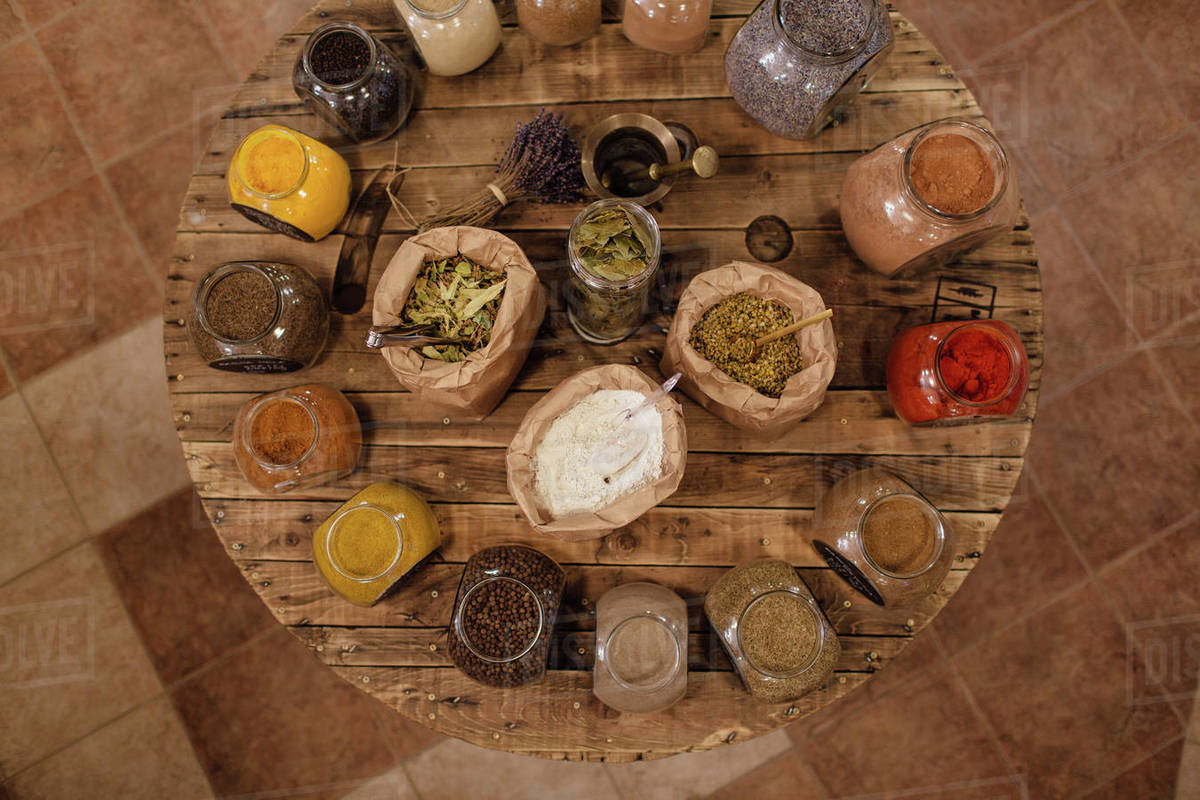 Variety of colorful dried herbs and spices displayed on round wooden ...