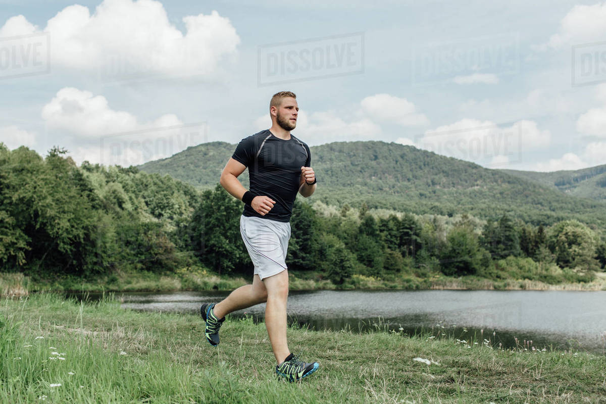 Male runner enjoying running across the country along a pond - Royalty ...