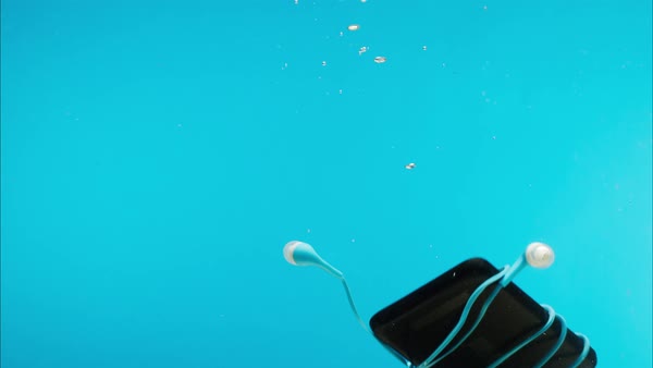 Drowning smartphone with headphones in water close-up, throwing mobile ...