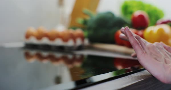 Woman hand turns on modern induction cooker. Close-up of a female hand ...
