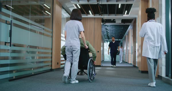 Back-view of caring professional female nurse in uniform helping ...