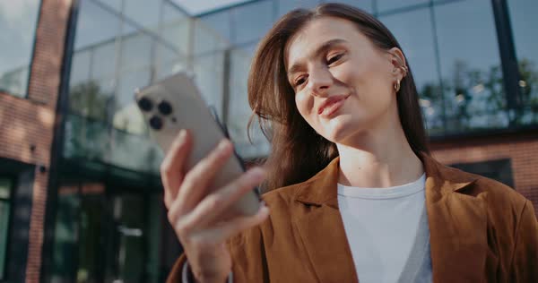 Cute Caucasian girl standing in front of building and using her ...