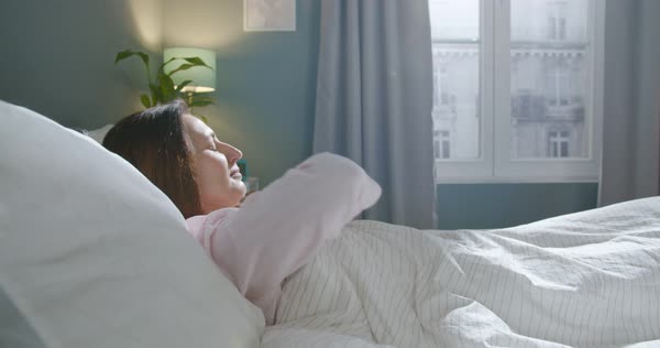 Side view of joyful Caucasian pretty woman sleeping lying in bed ...