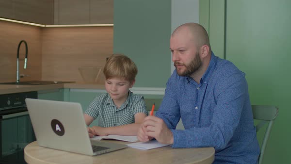 Dad helping his son with online studying. Family learning together ...