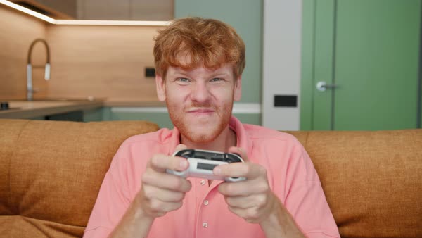 Close up of red hair man playing video game sitting on couch looking at ...