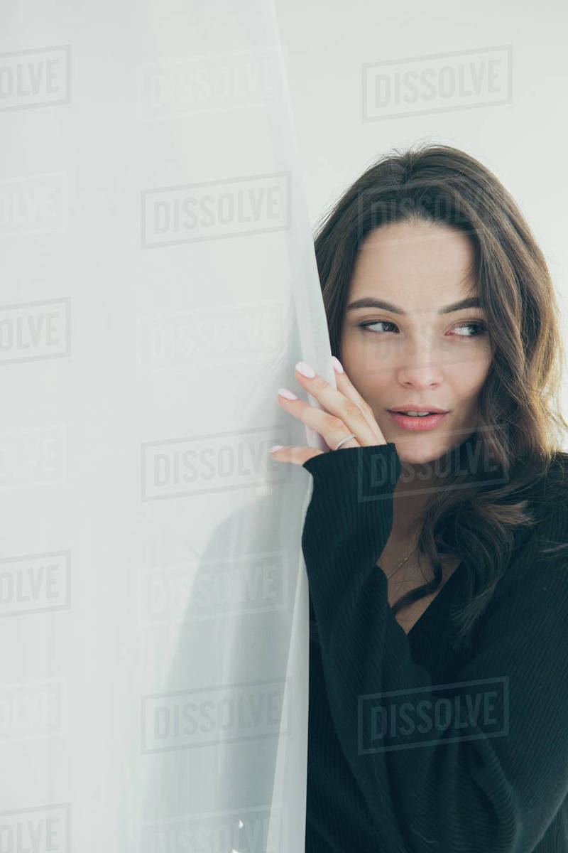 Portrait of young brunette woman in black shirt posing near transparent ...