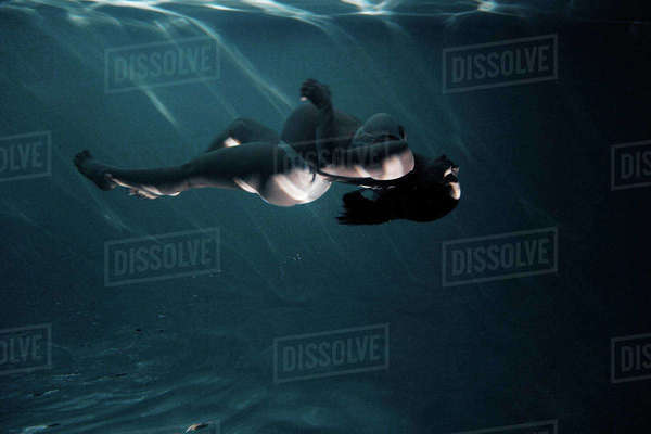Underwater shoot of beautiful pregnant woman swimming in water through ...