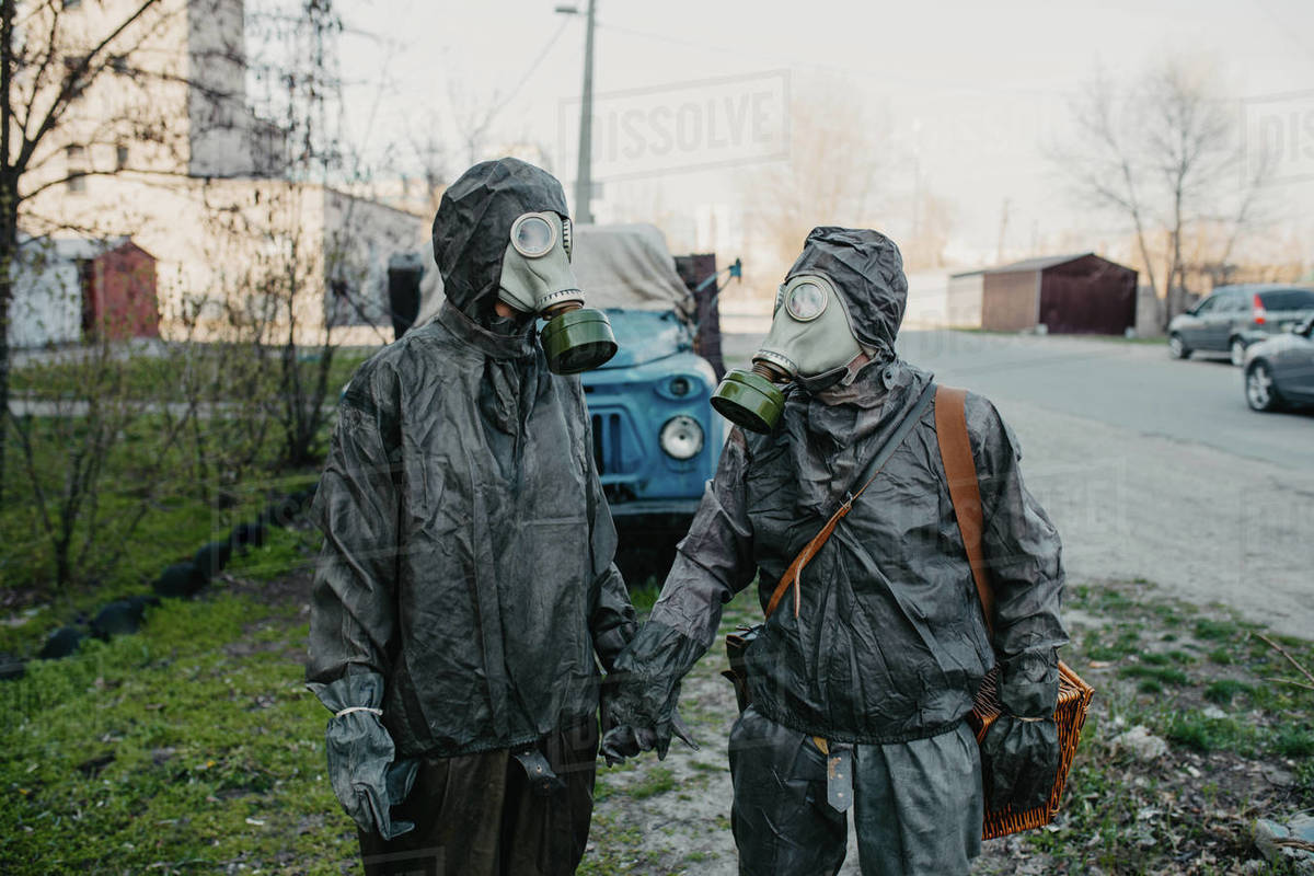 Couple in love holds hands in protective suits and gas masks. Concept ...