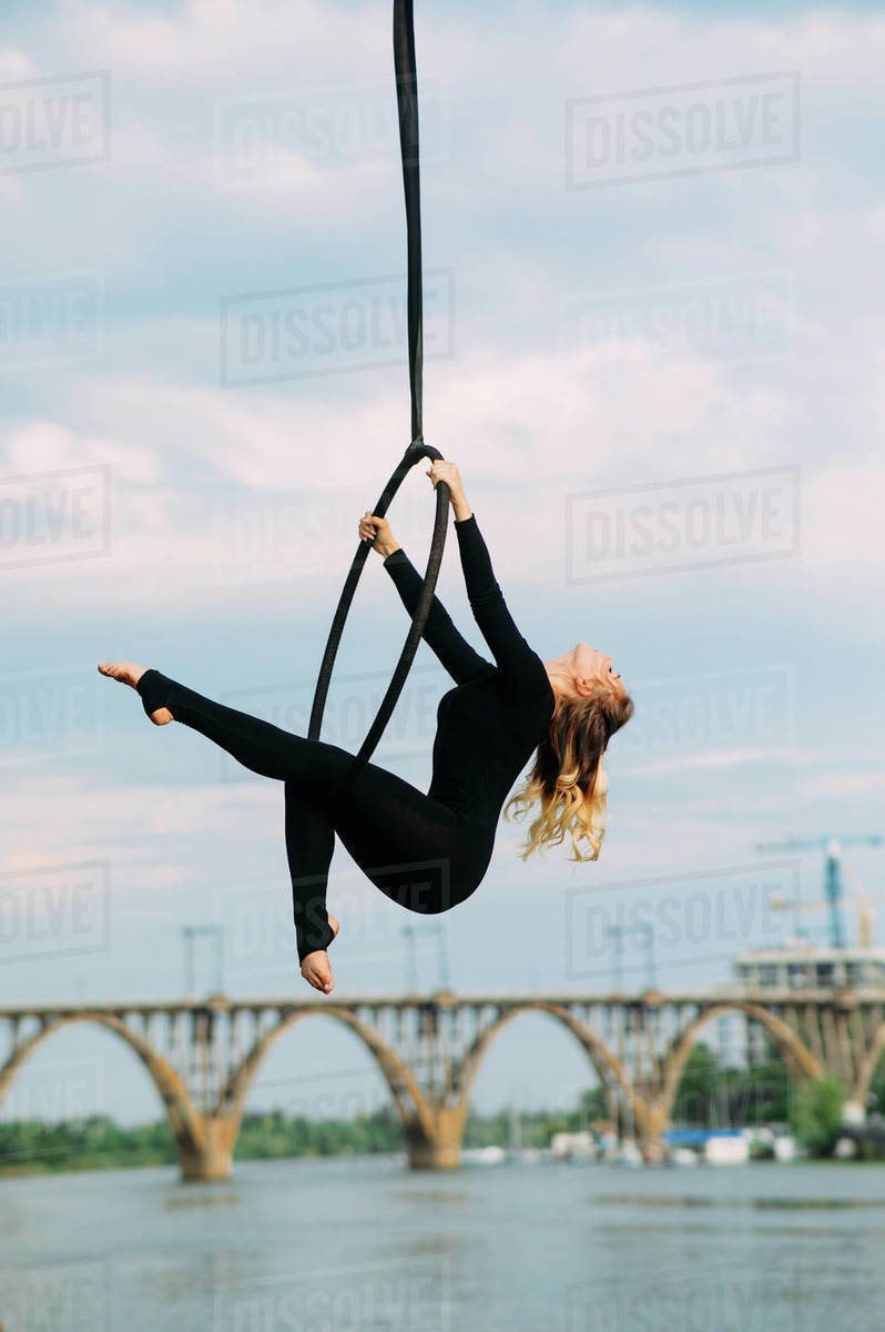 Woman aerialist performs acrobatic elements in hanging aerial hoop ...