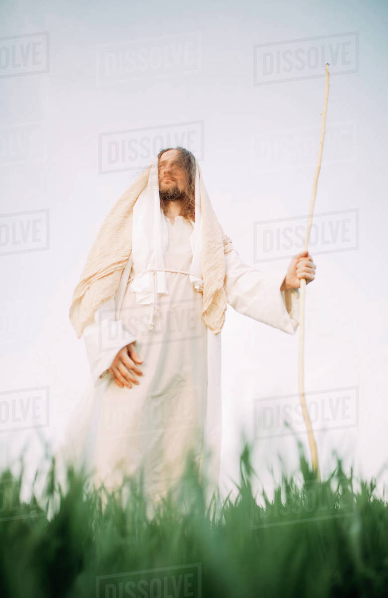 Prophet with wooden staff stands in meadow clothed in his traditional ...