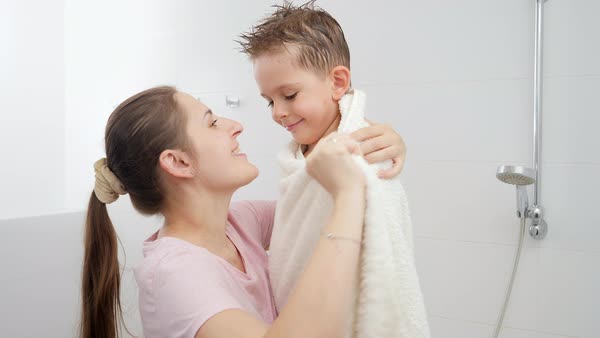 Caring mother drying her son with towel and hugging after bathing ...