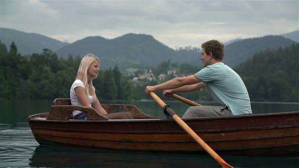Romantic couple on boat rowing in slow motion. Boy and girl in love ...