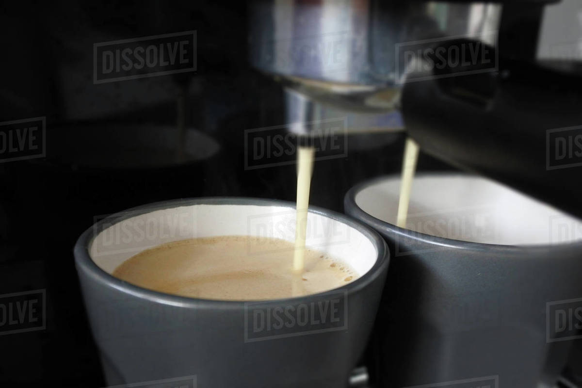Close up of coffee machine pouring Espresso into two coffee cups ...