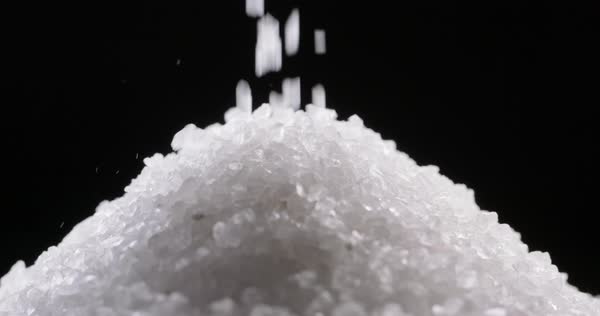 Close up shot of salt granules falling. Spice particles being dropped ...