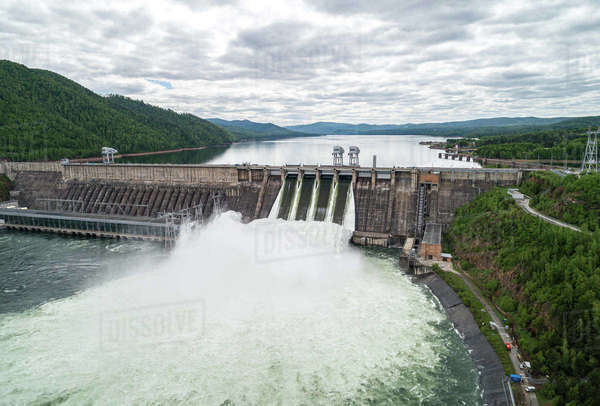 Aerial view of concrete dam releasing water into river on cloudy day ...