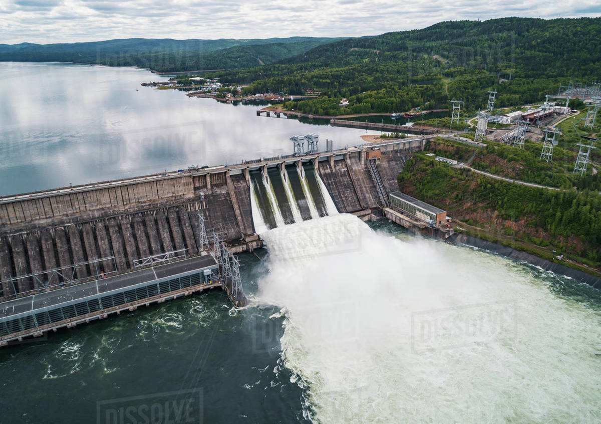Aerial view of concrete dam releasing water into river on cloudy day ...