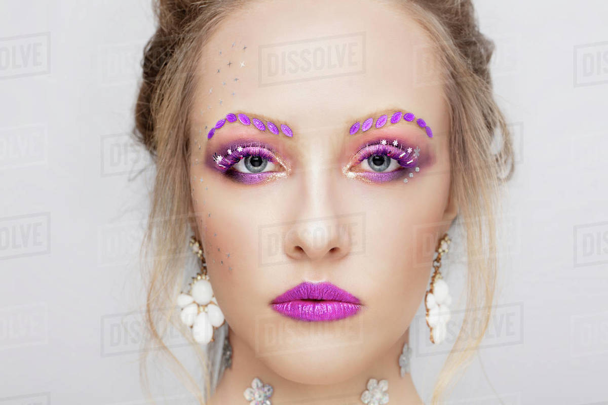The face of a young girl. Model with purple make-up. Fancy eyebrows ...