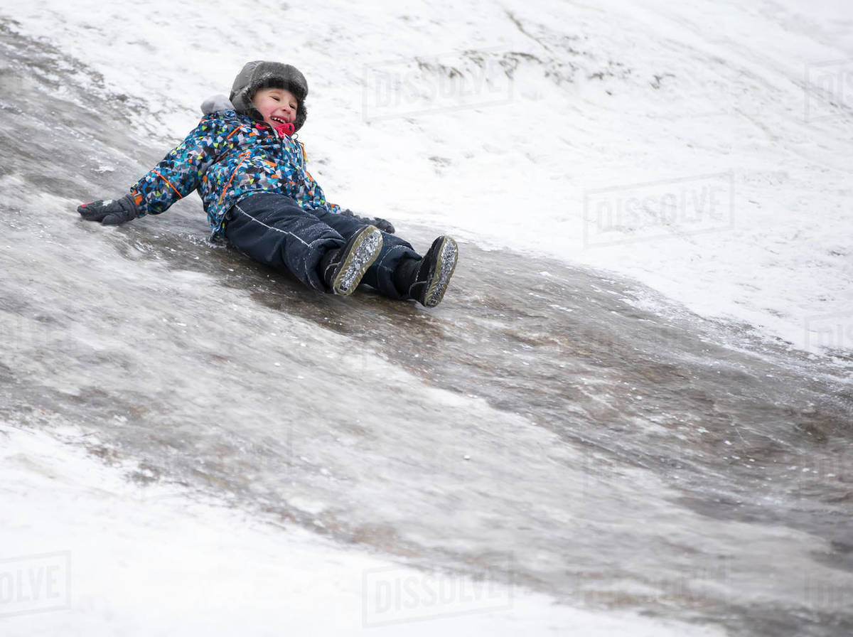 Child rides on an ice slide. Cheerful boy in the winter. - Royalty-free ...