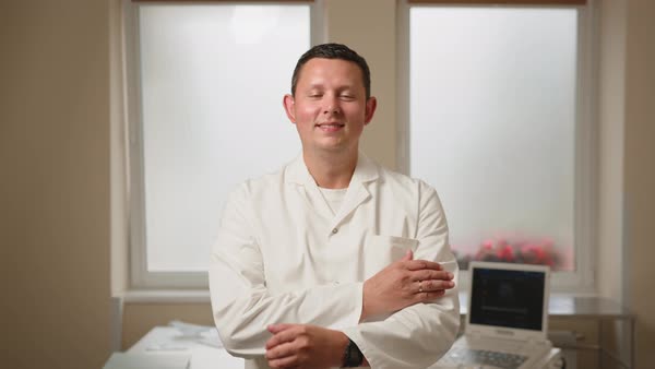 Portrait of experienced male gynecologist in white lab coat standing at ...