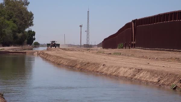 A tributary of the Colorado River flows along the border wall between ...