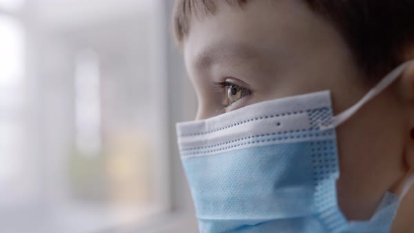 Sick child in mask standing near the window, children's health ...
