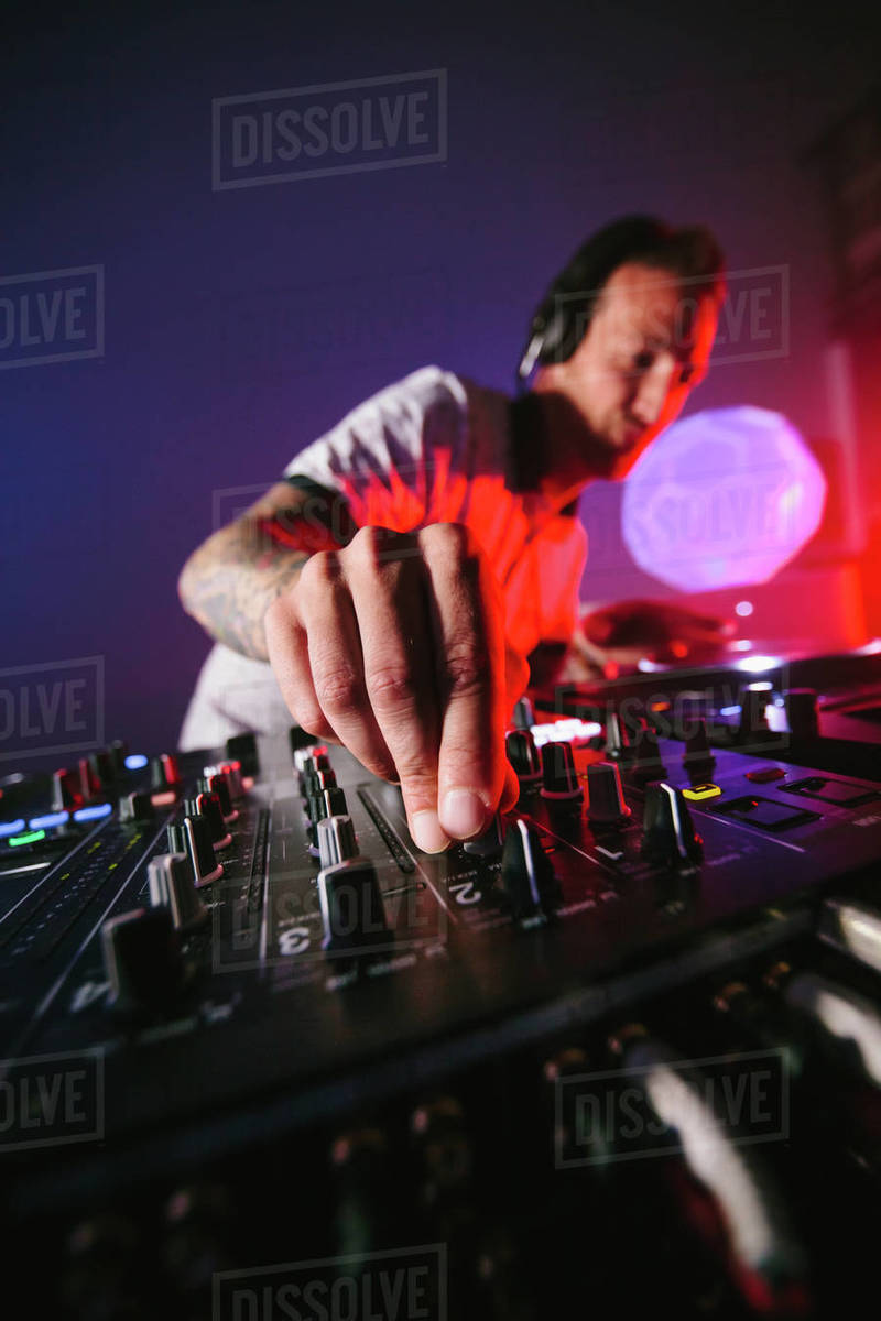 Close up of hands of a male DJ playing the mixer table for techno music ...