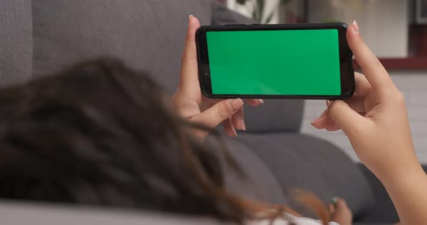 Woman on the living room couch watching something on her cell phone ...