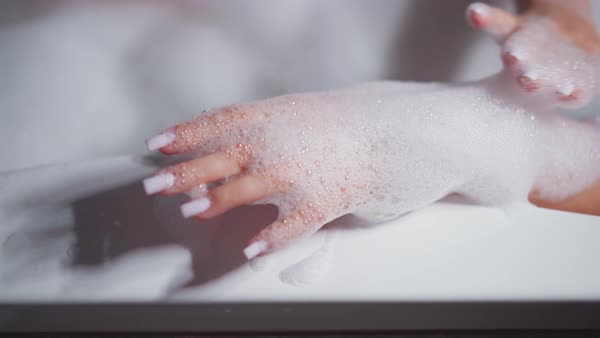 Woman applies foam on manicured hand in bathtub closeup. Elegant lady ...