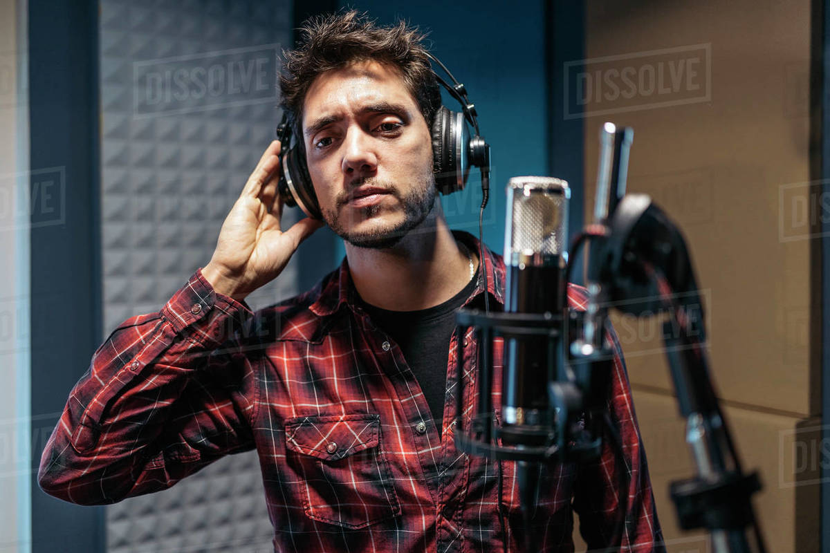 Young musician singing into microphone while working on songs during a ...