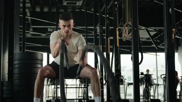 Active man training with battle ropes waves in gym bodybuilding muscle ...