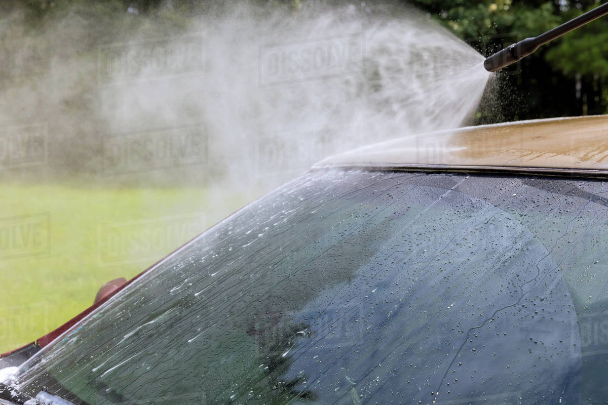 Detail on car front being washed with jet water in a car wash in a self ...