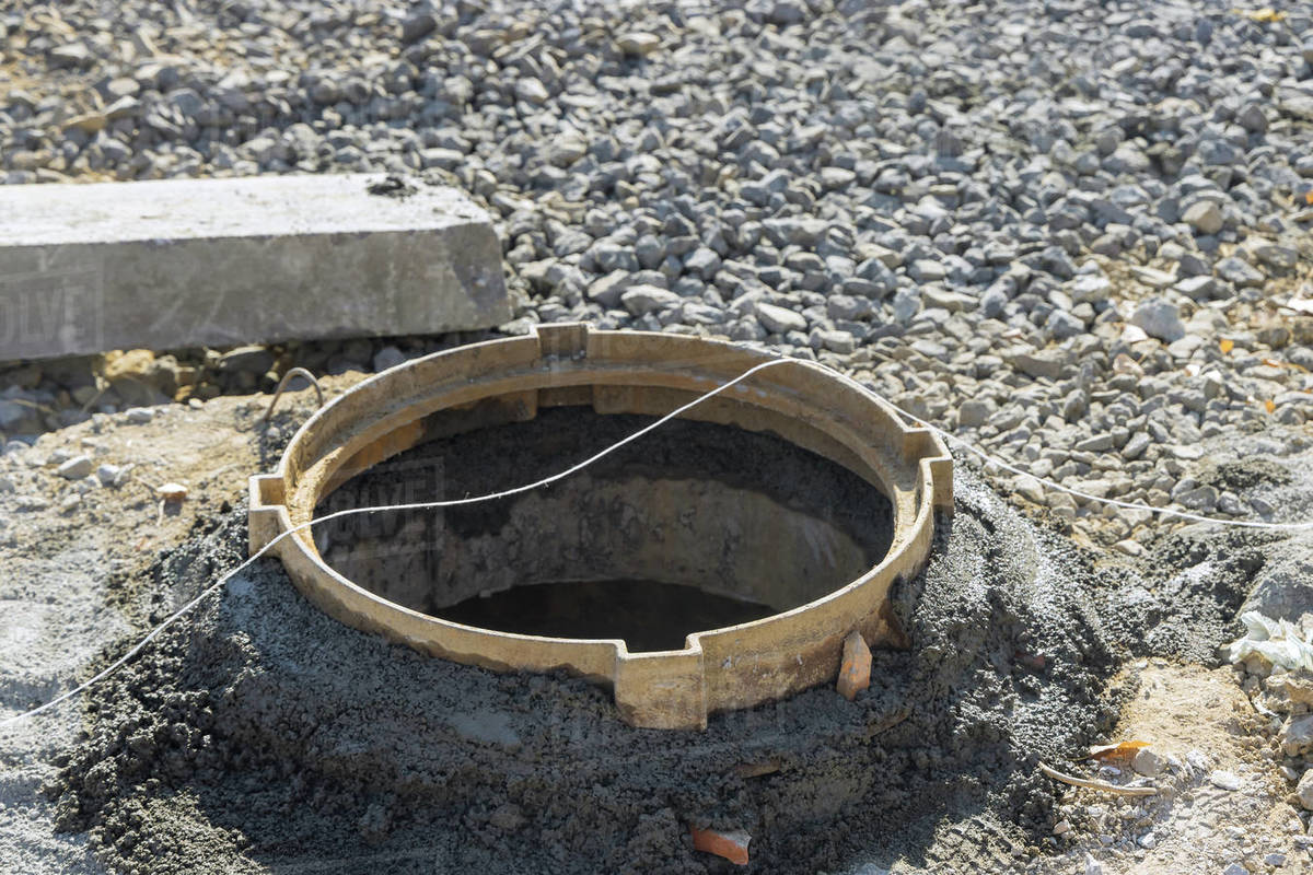 Sewerage construction with utility worker installing underground well ...