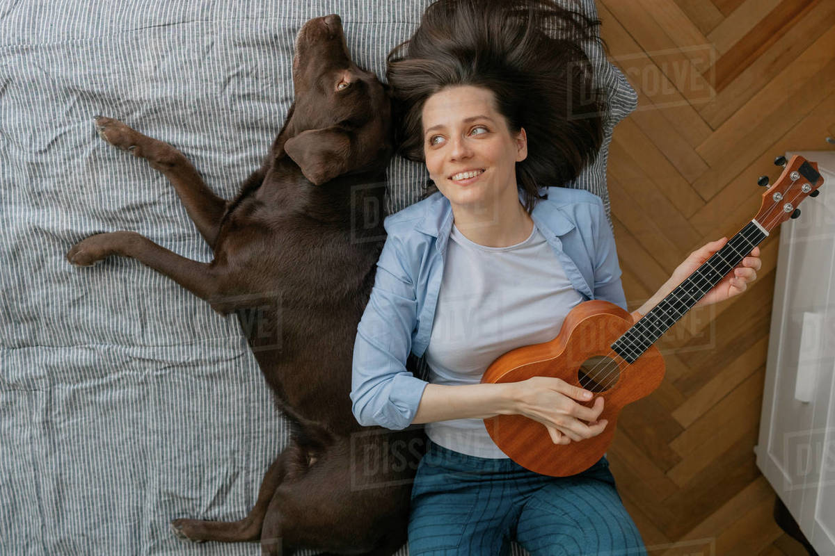 A woman and her retriever dog lie on a bed and rest at home. a woman ...