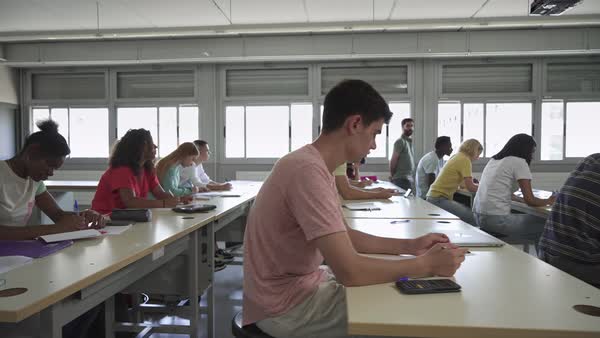 Teacher walks in the classroom explaining Lesson to class of Teenager ...