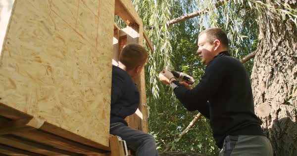 Happy father and son building a tree house in the garden - 4K Royalty ...