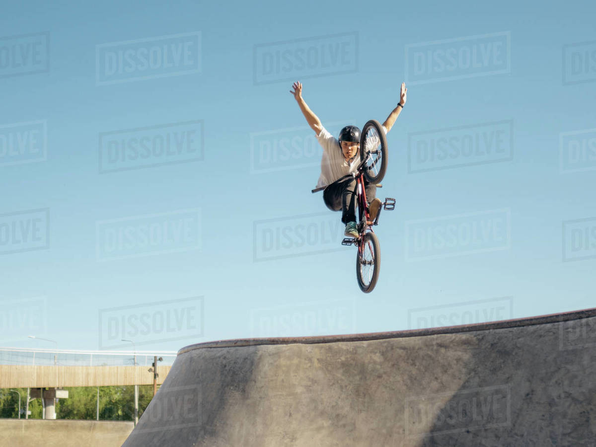 BMX bicycle rider flying and doing stunt No Hand in quarter pipe ...