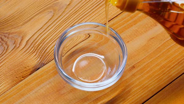 Pouring Oil Liquid. Oil is poured from a bottle into a cup. Olive oil ...