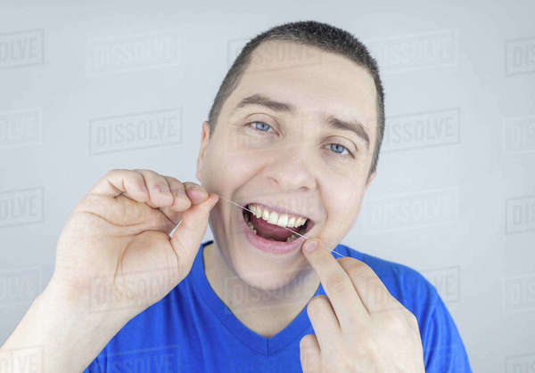 Dental floss close up. A man in front of a mirror brushes his teeth ...