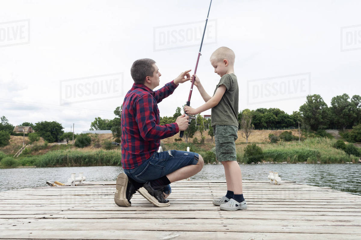 Father and son fishing. Dad shows his son how to hold the spinning and ...