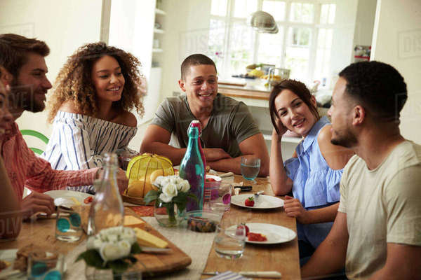 Young adult friends at a table talking over lunch at home - Stock Photo ...