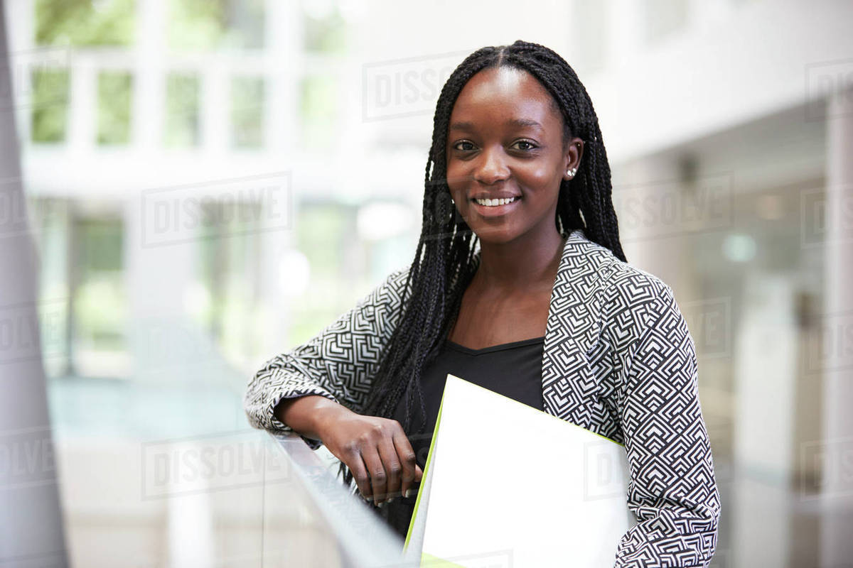 Smiling young black female student in university foyer - Royalty-free ...