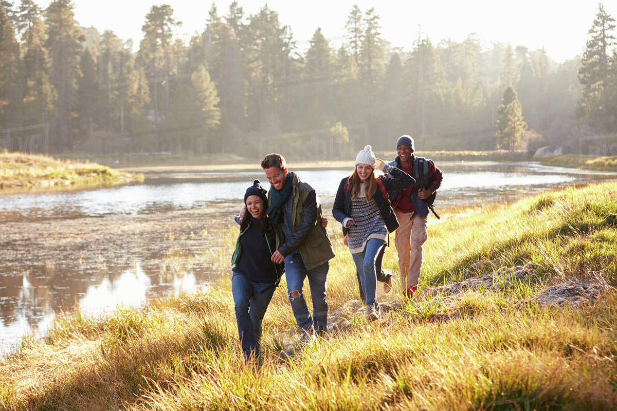 Four friends having fun walking beside a lake - Royalty-free Stock ...