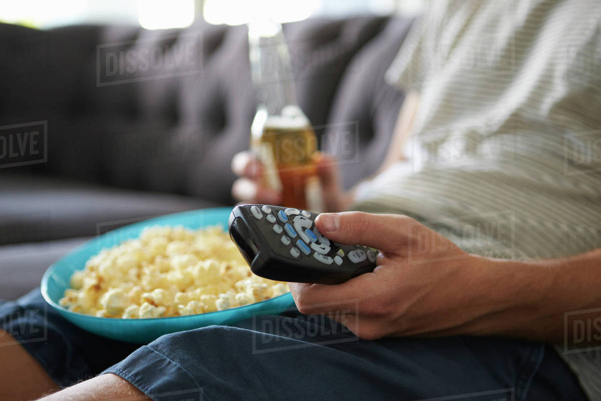 Man Sitting On Sofa Holding TV Remote And Bottle Of Beer - Stock Photo ...