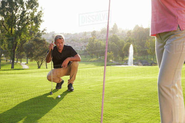 Male Golfer Lining Up Putt On Green - Stock Photo - Dissolve