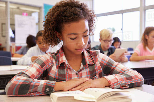 Schoolgirl reading at her desk in an elementary school class - Royalty ...