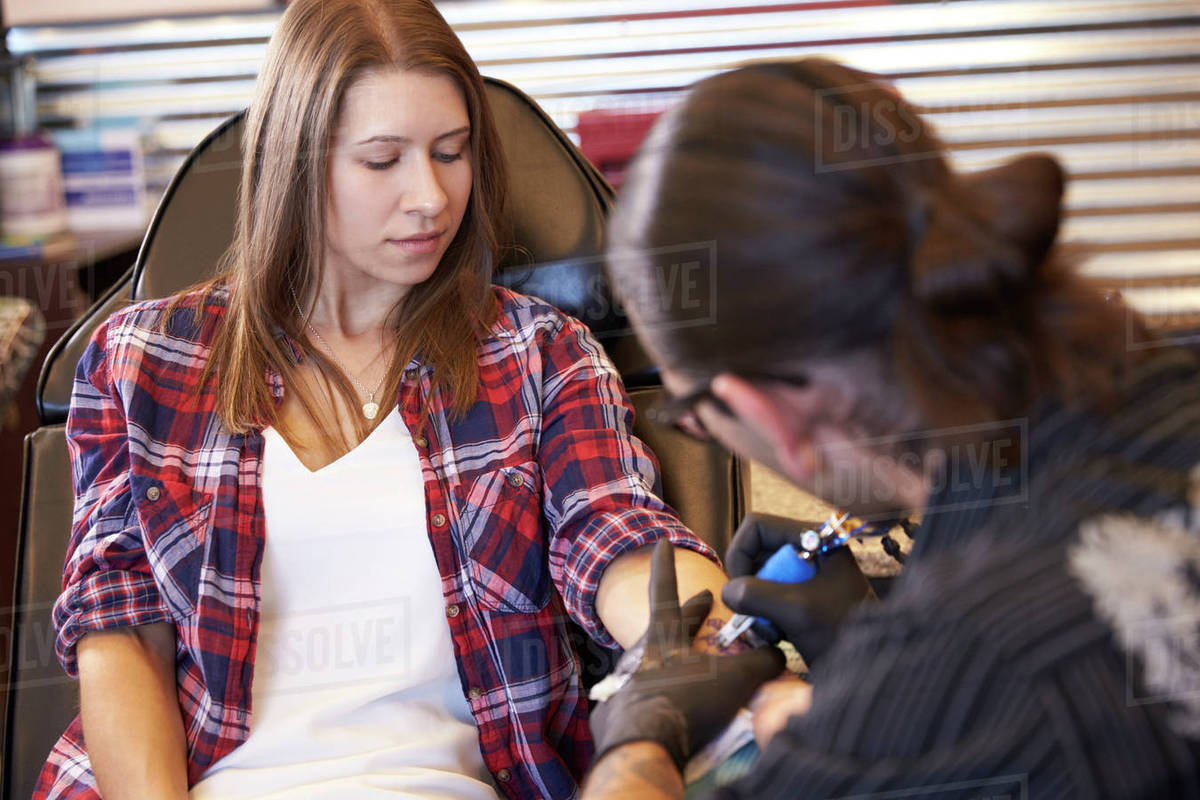 Woman sitting in chair having tattoo on arm in parlor - Stock Photo ...