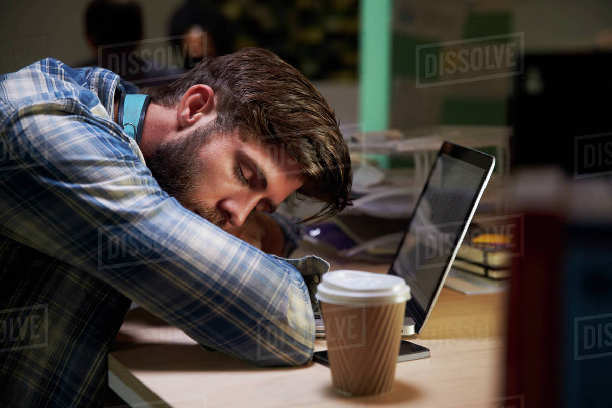 Male office worker asleep at desk working late on laptop - Royalty-free ...