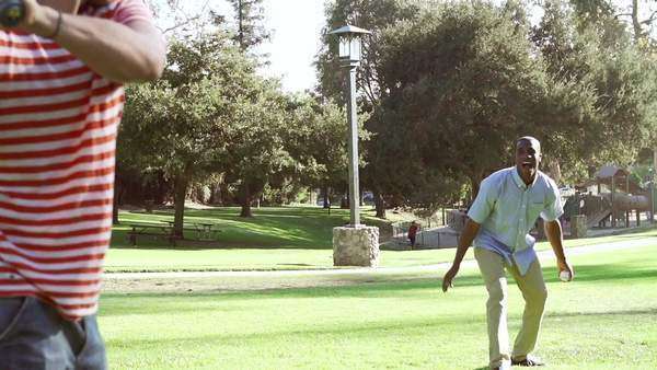 Slow motion sequence of two male friends playing baseball in park ...