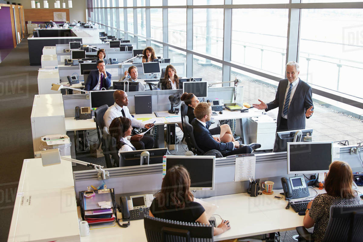 Senior male manager addressing workers in open plan office - Royalty ...